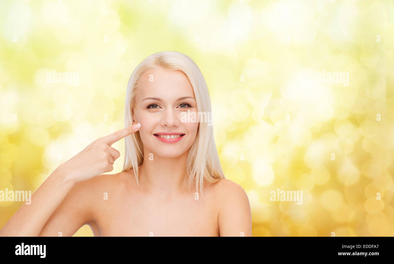 smiling young woman pointing at her cheek Stock Photo - Alamy