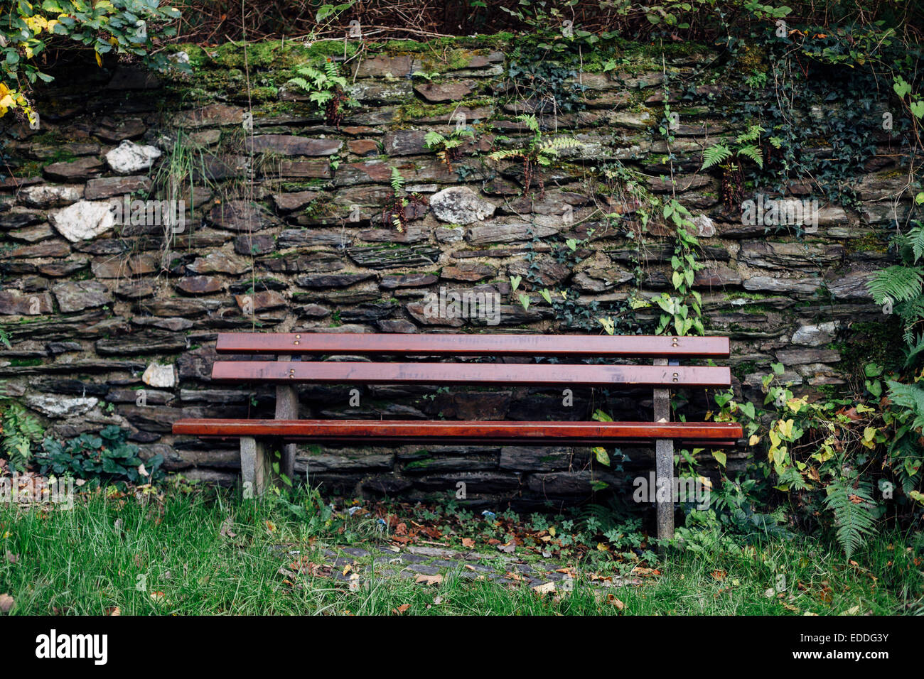 Bench in front of natural stone wall Stock Photo - Alamy