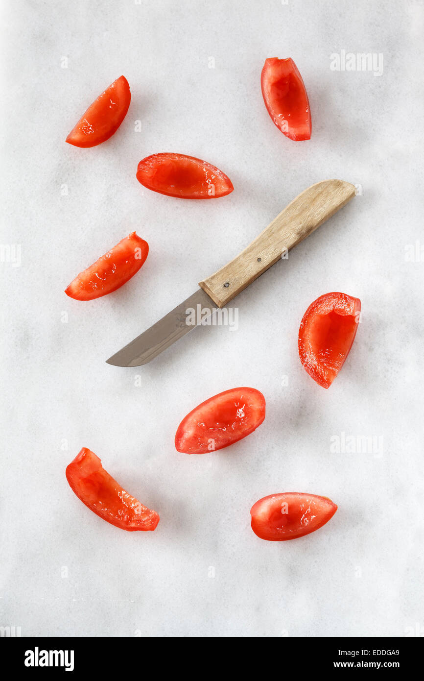 Slices of pitted tomato and a kitchen knife on white marble Stock Photo ...