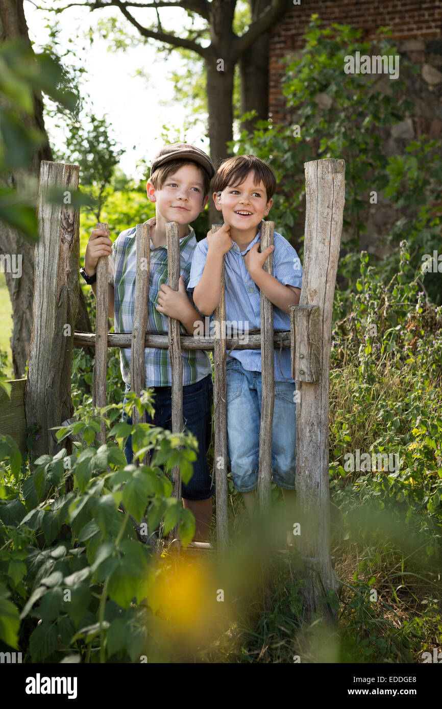 Portrait of two little boys standing behind a wooden fence Stock Photo ...