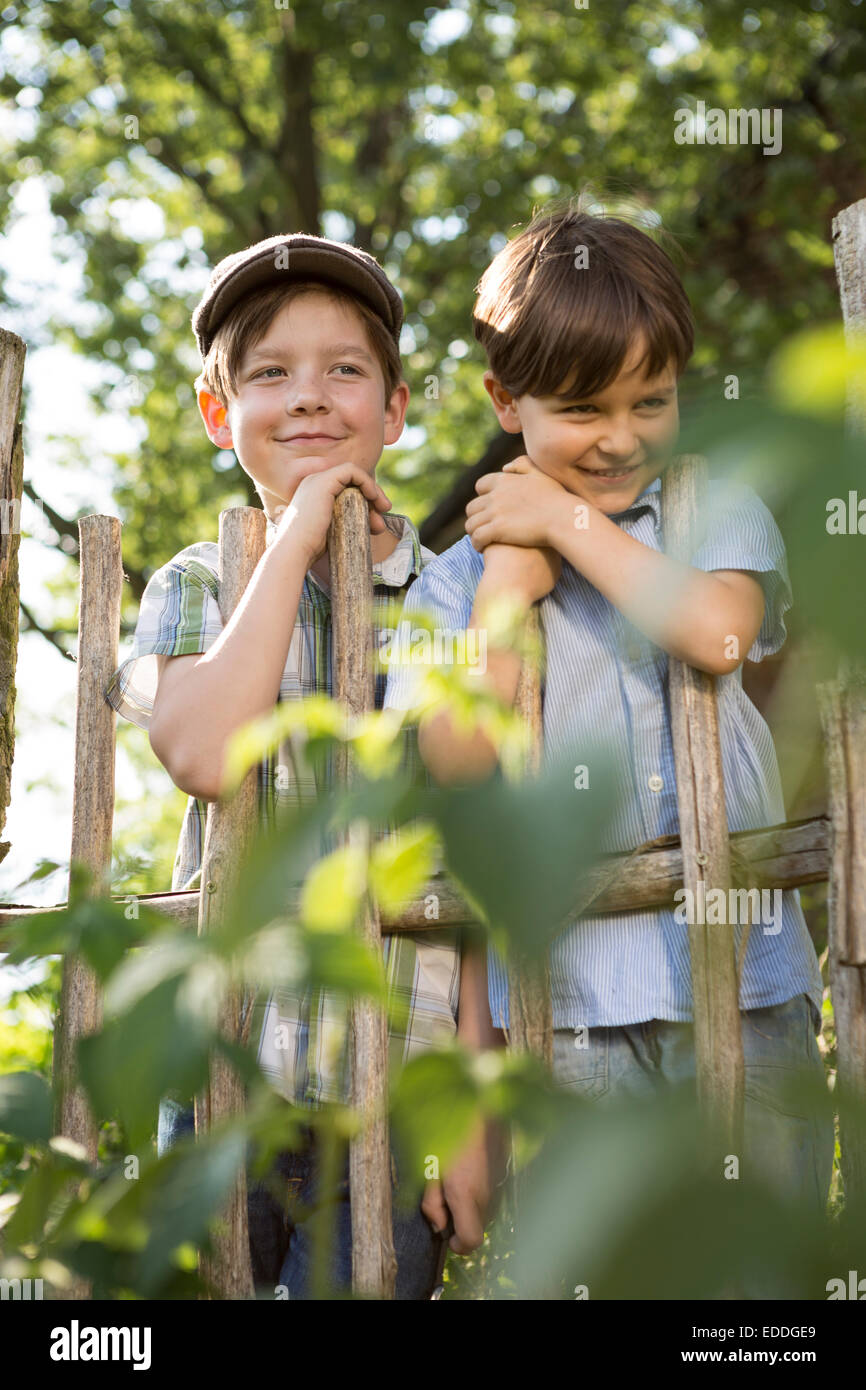 Portrait of two smiling boys standing behind a wooden fence Stock Photo ...