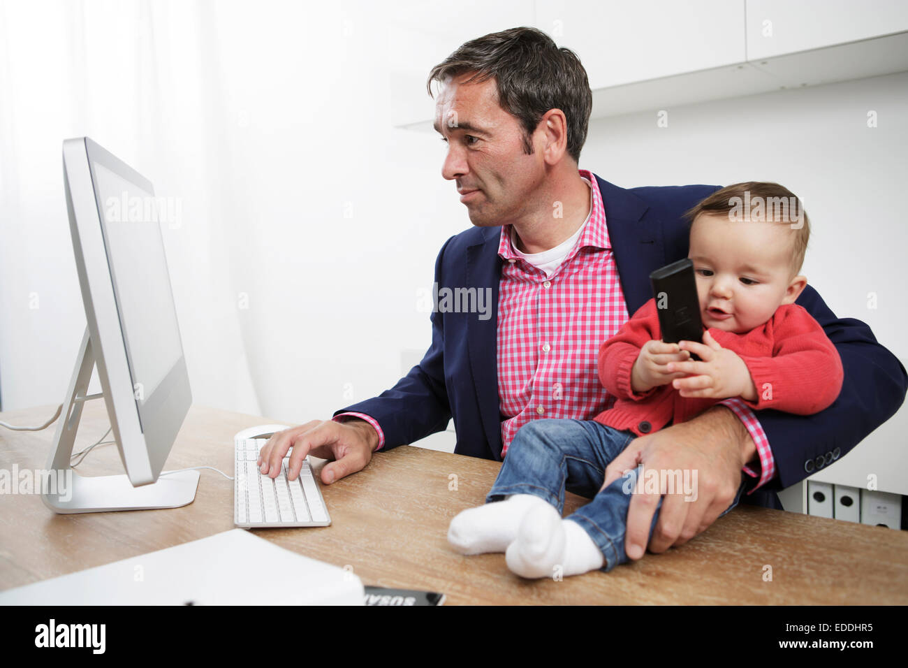 Businessman with baby boy working from home Stock Photo - Alamy
