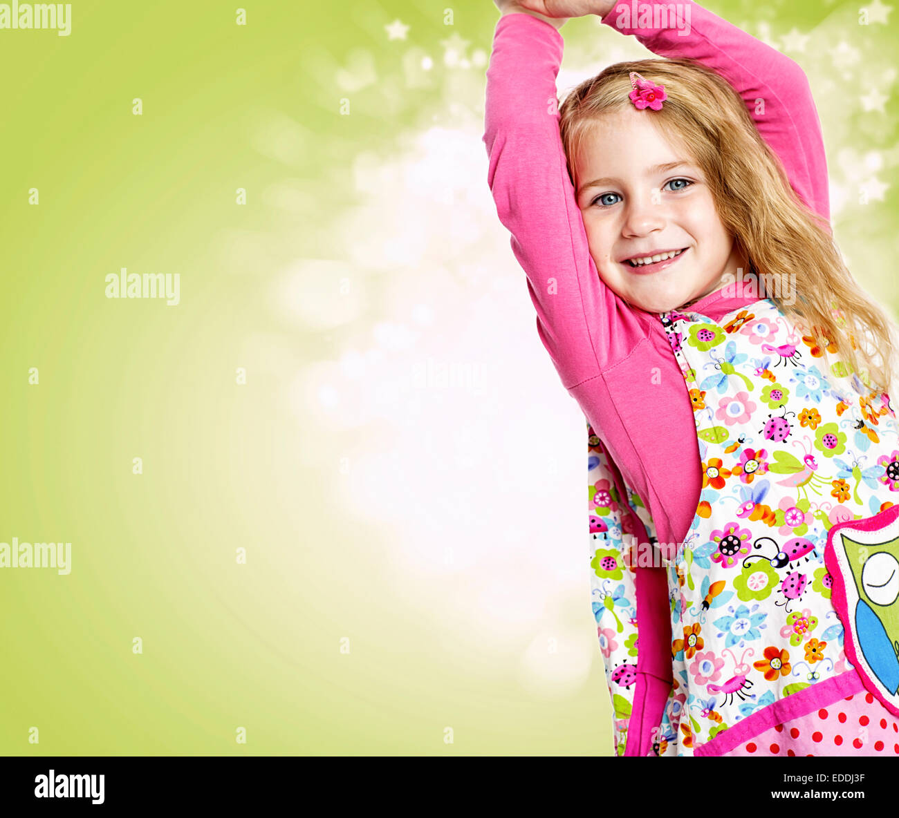Portrait of smiling girl with outstretched arms in front of light green ...