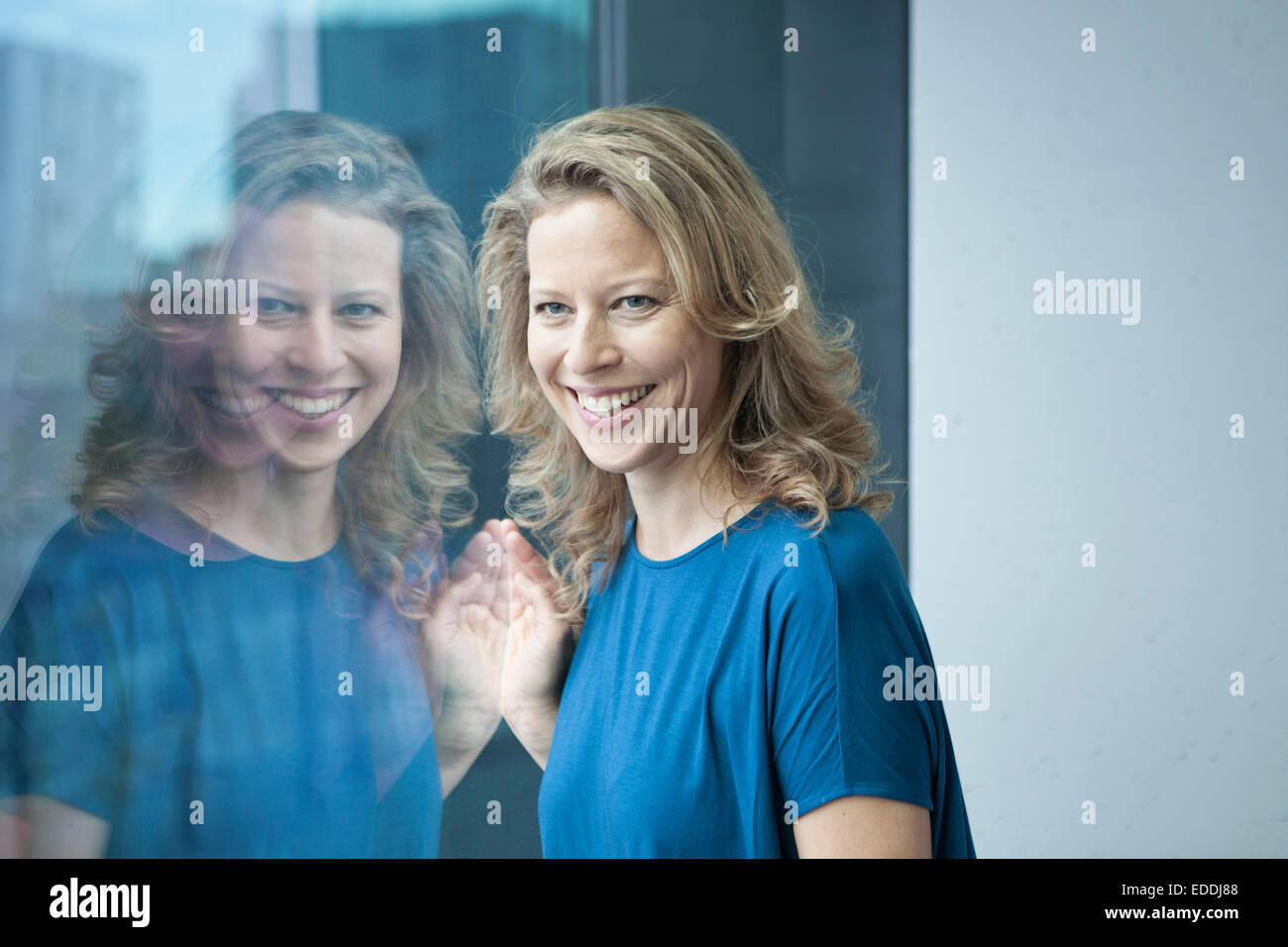 Portrait of smiling mature woman looking through window Stock Photo - Alamy