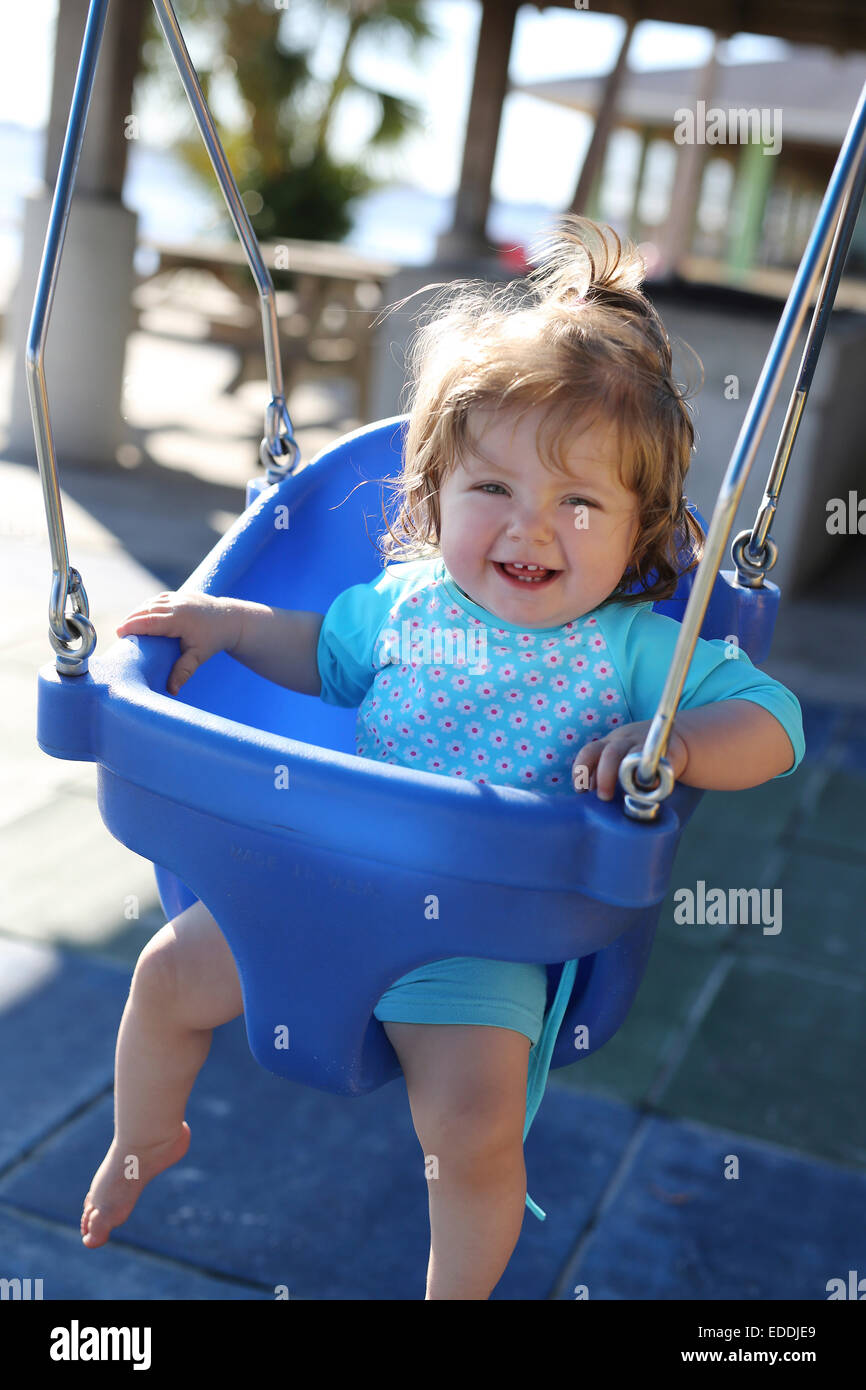 Smiling baby girl sitting on blue baby swing Stock Photo - Alamy