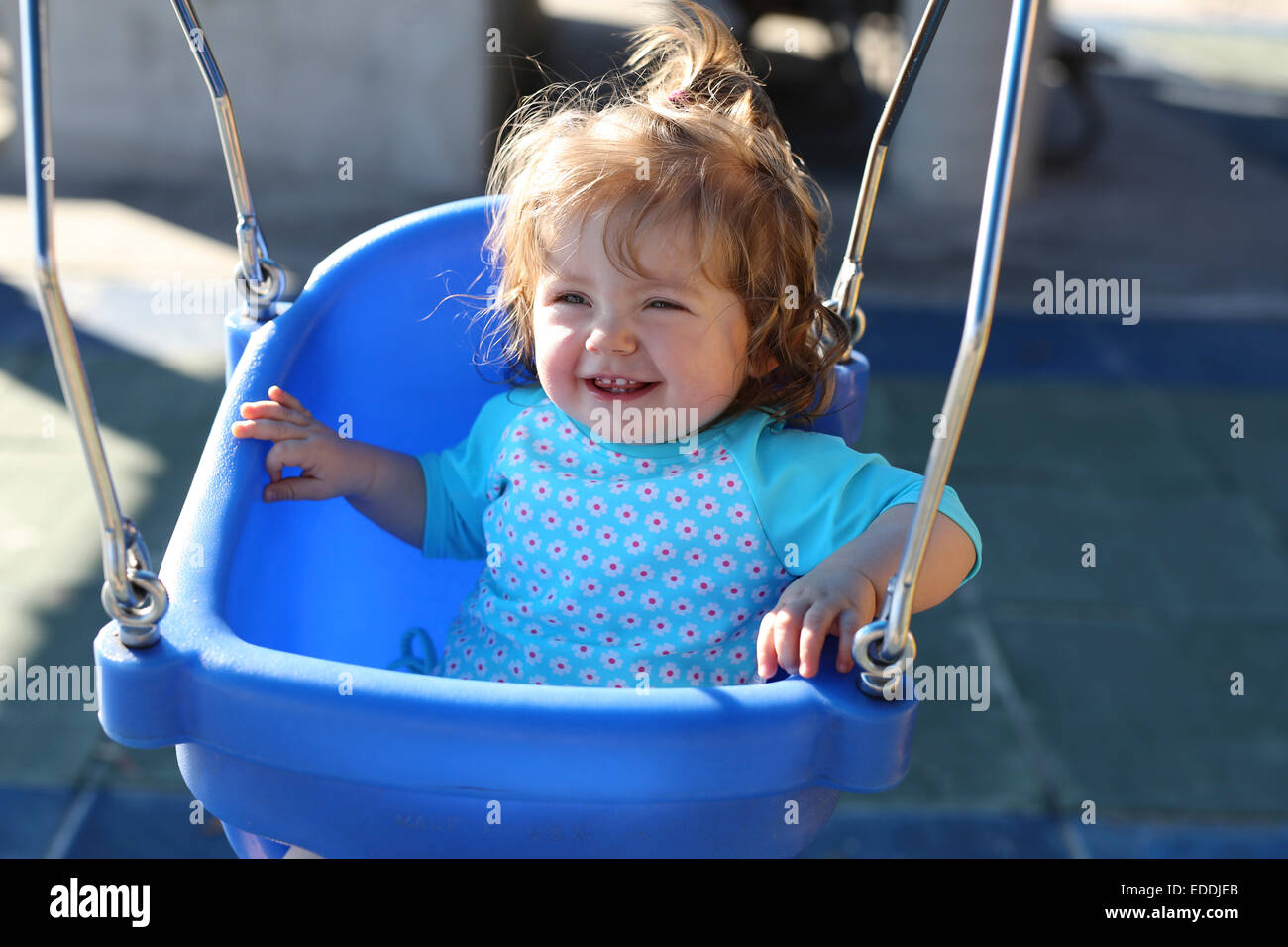 Portrait of smiling baby girl sitting on blue baby swing Stock Photo ...