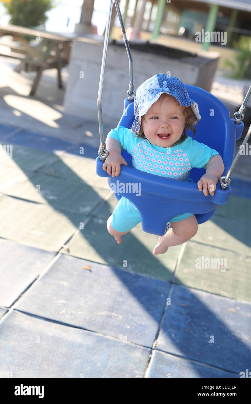Smiling baby girl sitting on blue baby swing Stock Photo - Alamy