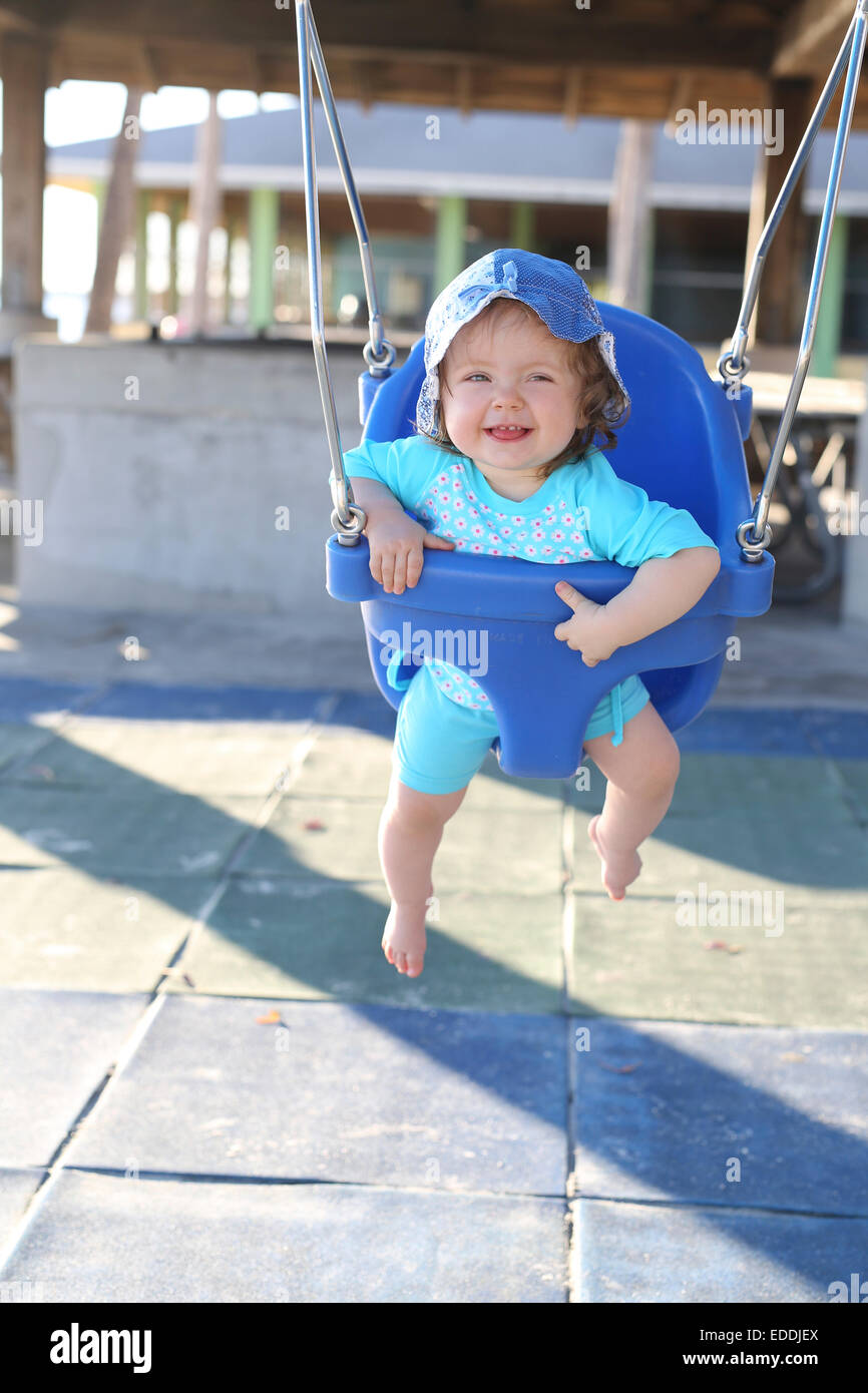 Smiling baby girl sitting on blue baby swing Stock Photo - Alamy