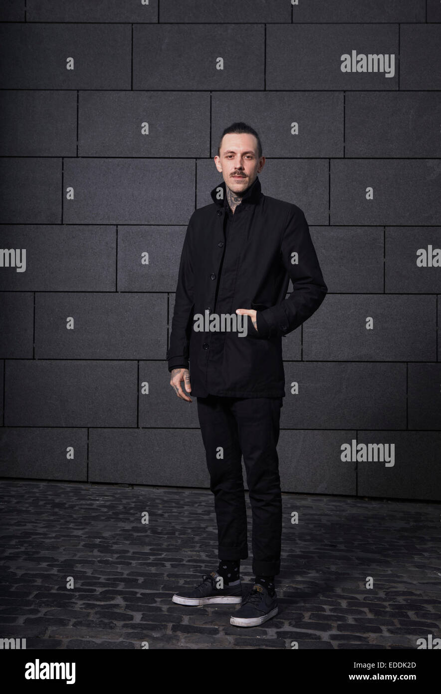 Portrait of black dressed man in front of grey background Stock Photo ...