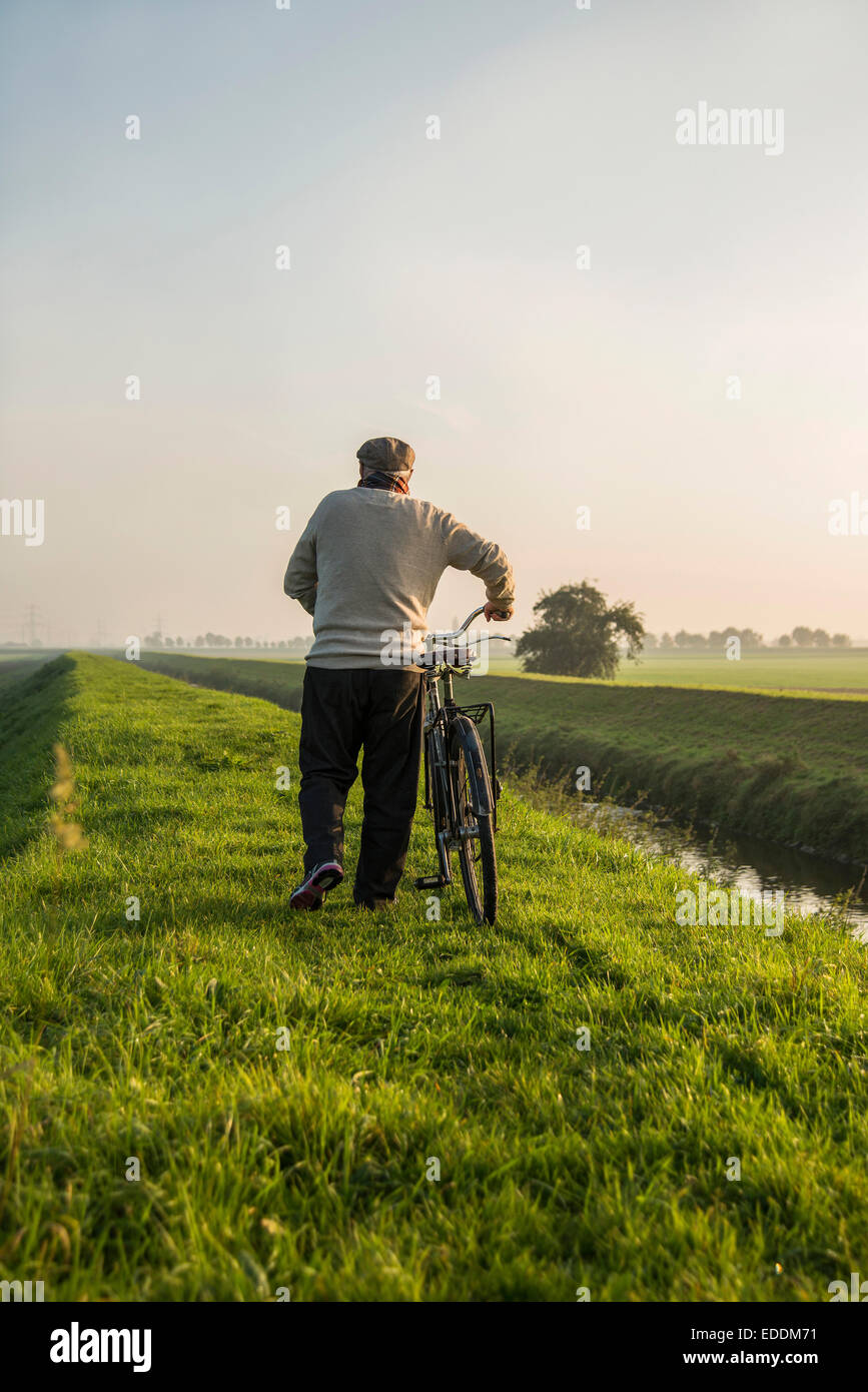 Senior man in rural landscape pushing bicycle Stock Photo - Alamy