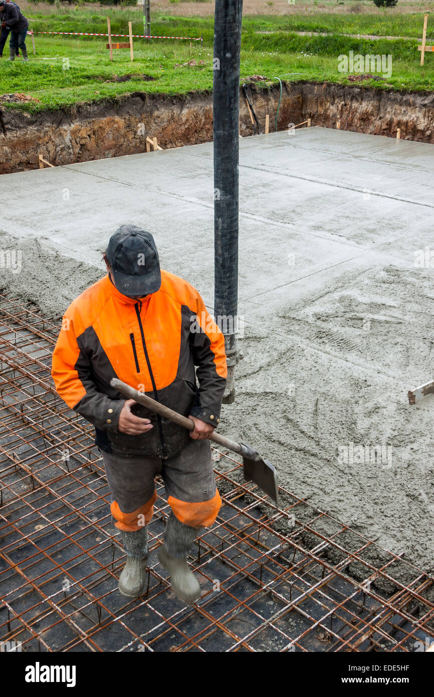 Worker pouring concrete mix into reinforced structure at the building ...