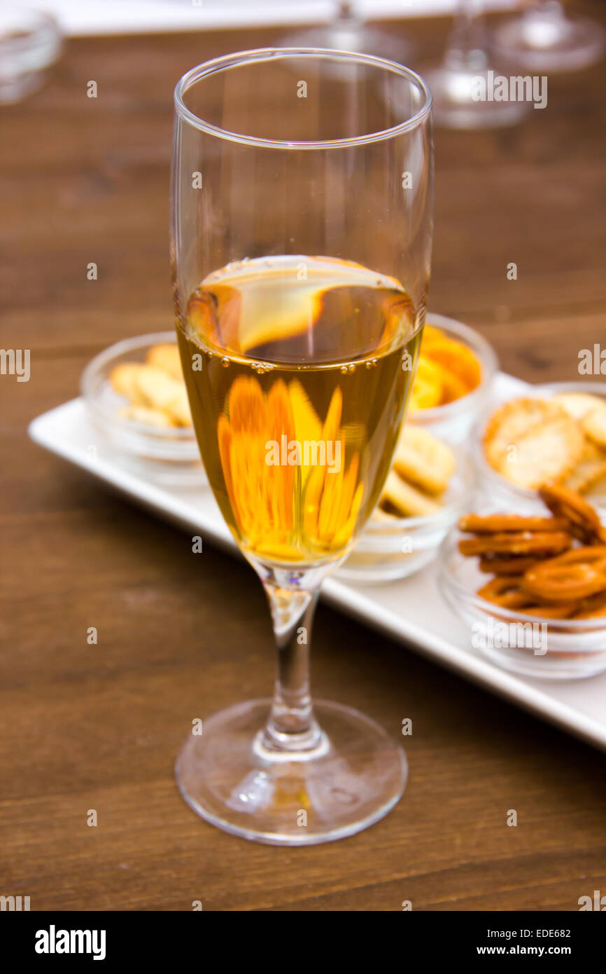 Flute with aperitif and pretzels on wooden table seen close Stock Photo ...