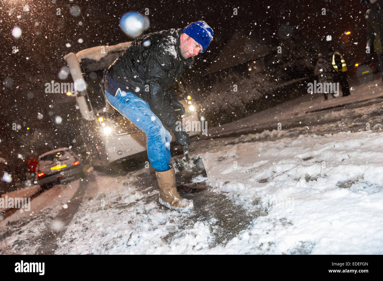 Man clearing a path for a stranded coach stuck on a hill due to snowy ...