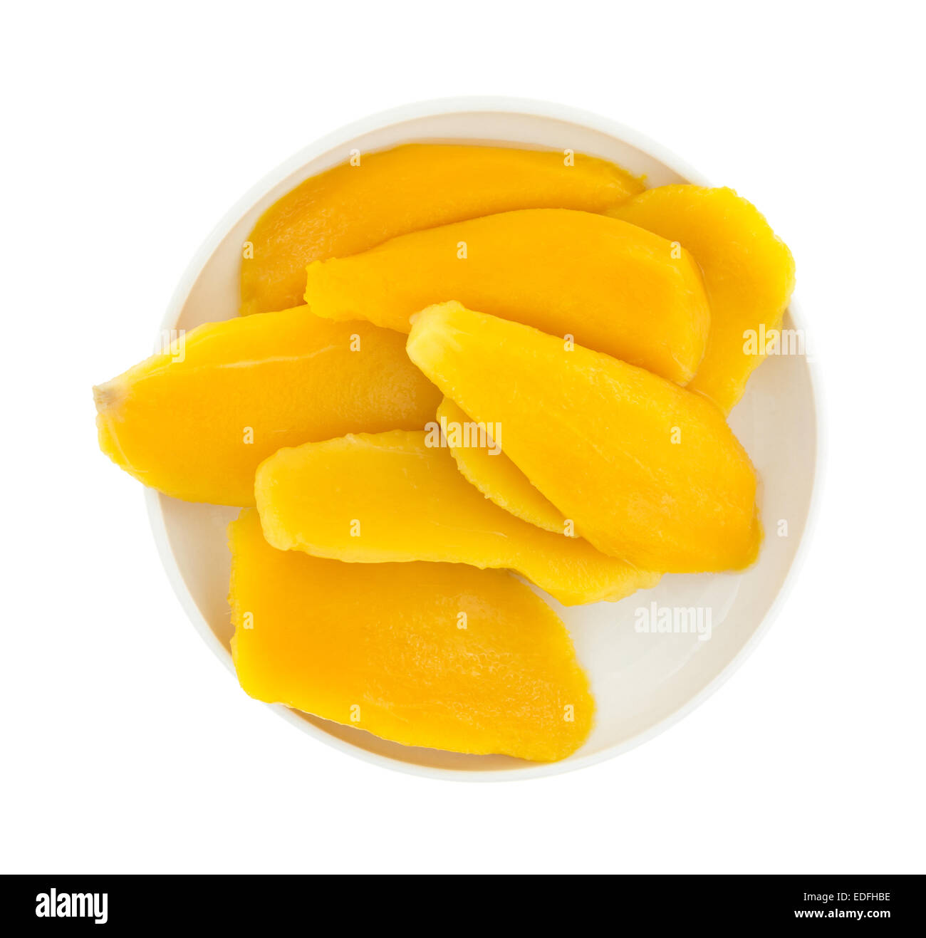 Top view of a plate of canned mango slices atop a white background ...