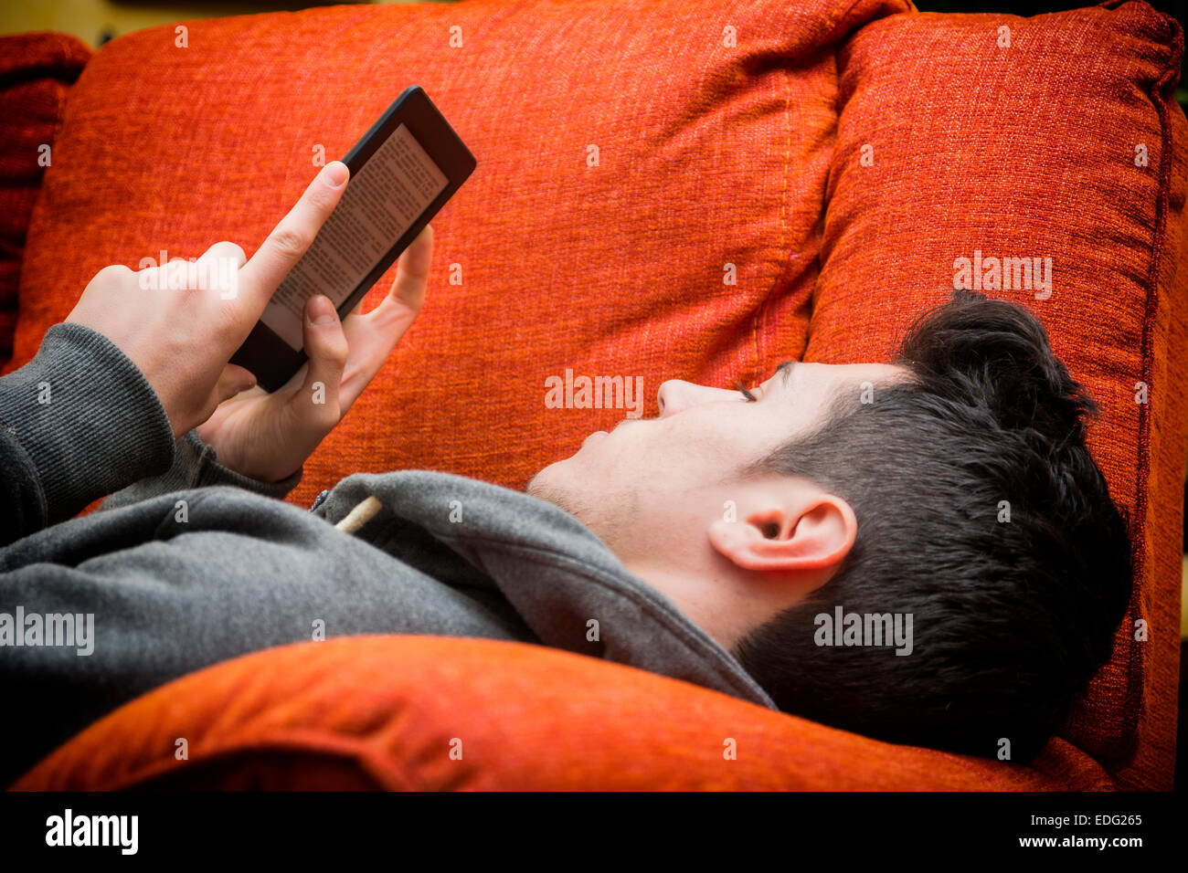 Handsome young man at home reading with ebook reader Stock Photo - Alamy