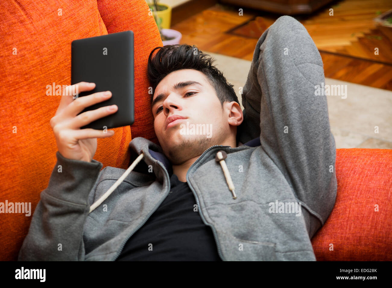 Handsome young man at home reading with ebook reader Stock Photo - Alamy