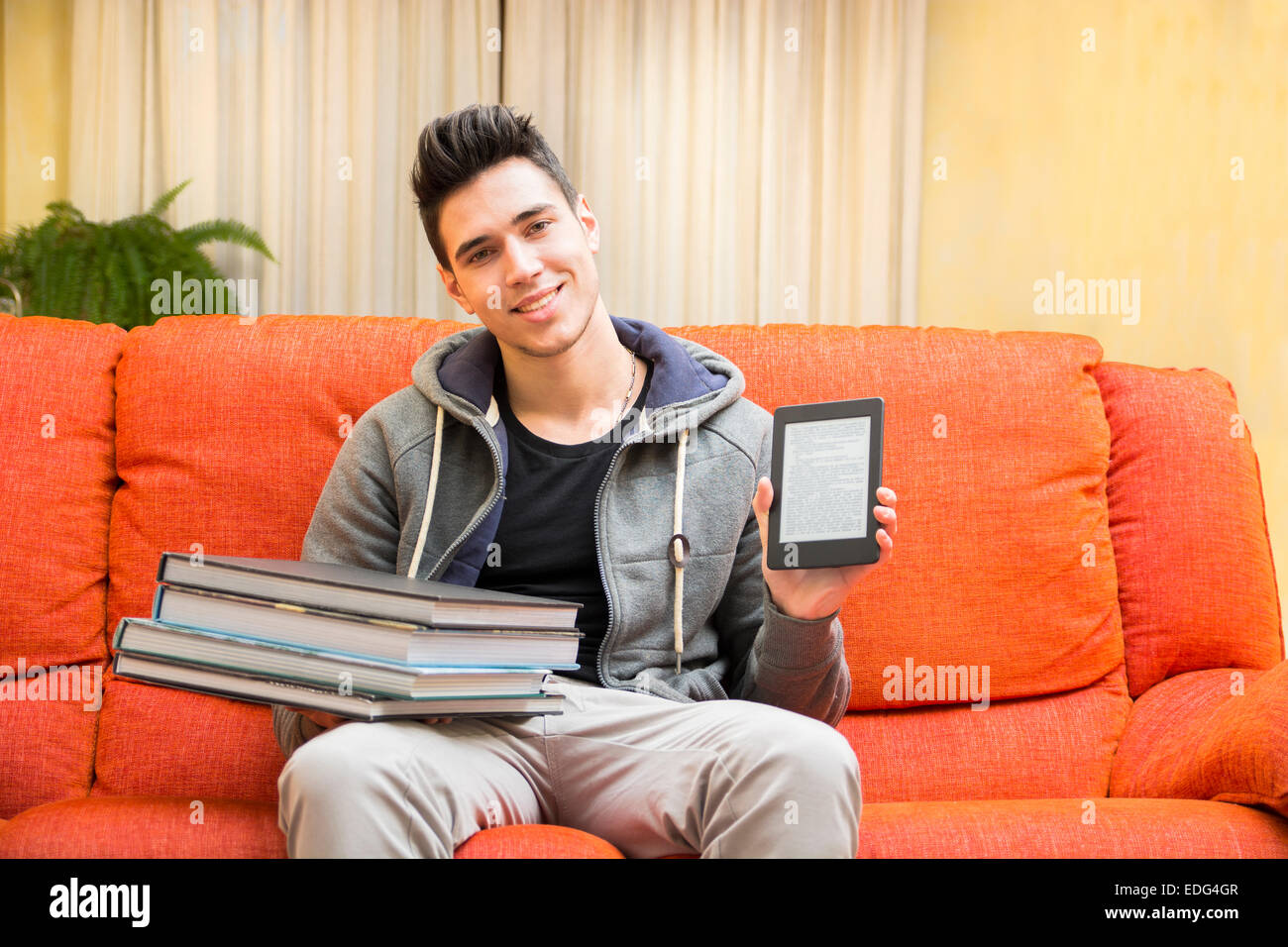 Young man showing difference between ebook reader and heavy books Stock ...