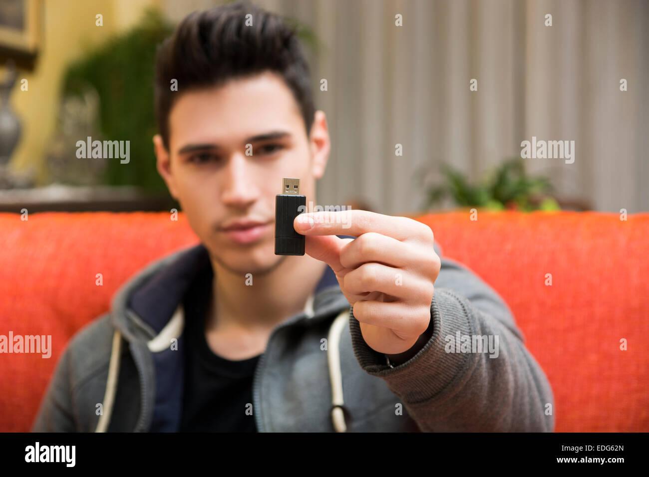 Handsome young man showing USB key in his hand, focus on the electronic ...