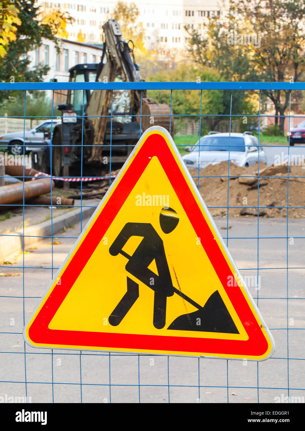 Roadworks red and yellow triangle sign on the metal fence. Road under ...