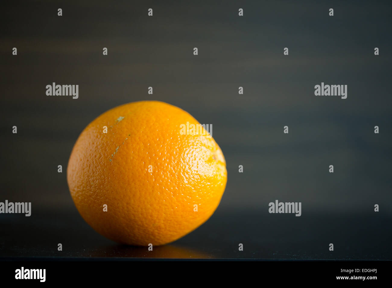 Single orange in front of a wooden background in a closeup view Stock ...