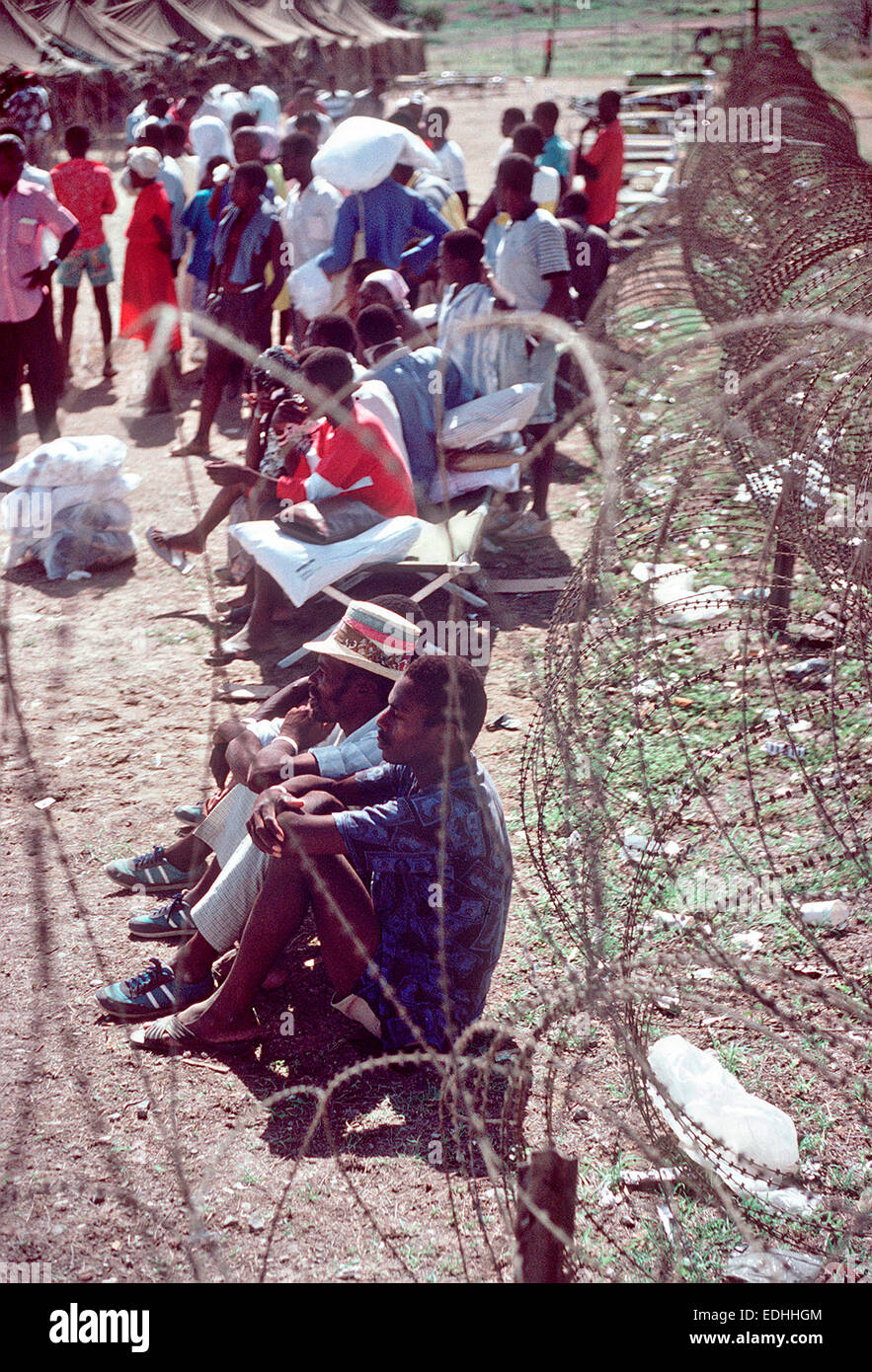 Haitian migrants wait at a temporary refugee camp after being ...