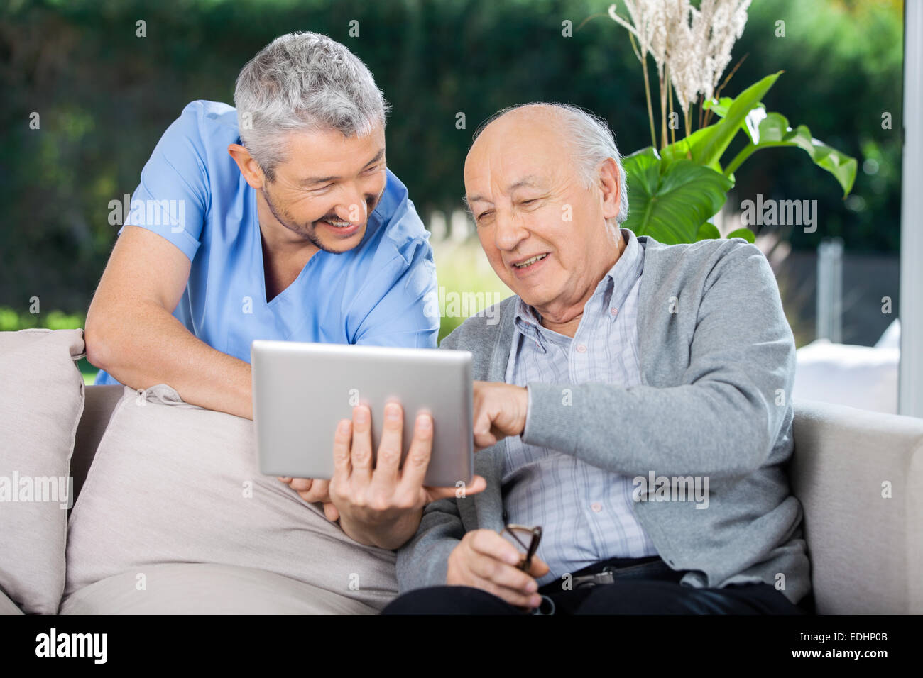 Male Nurse And Senior Man Smiling While Using Tablet Computer Stock ...