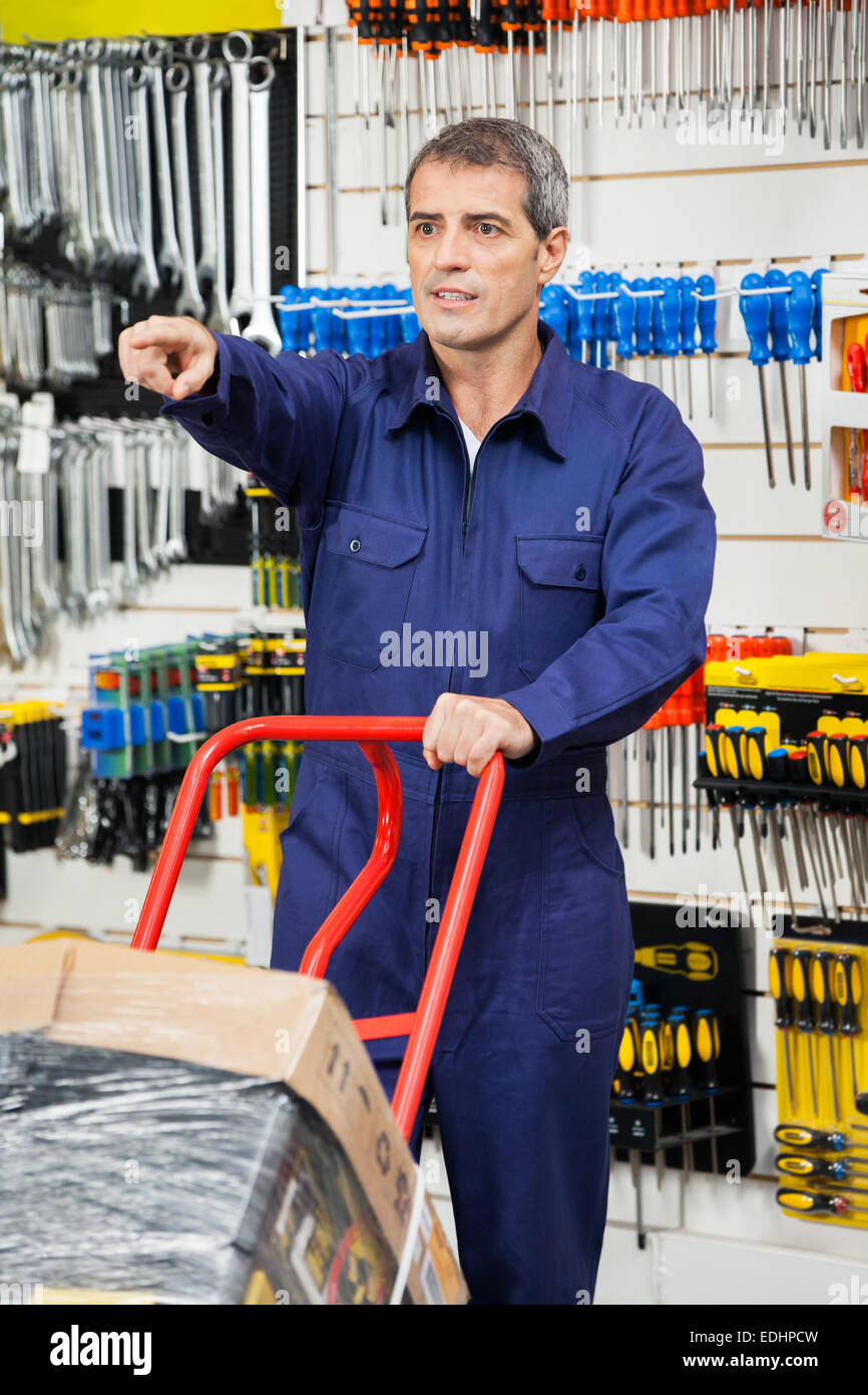 Worker With Trolley Pointing In Hardware Shop Stock Photo - Alamy