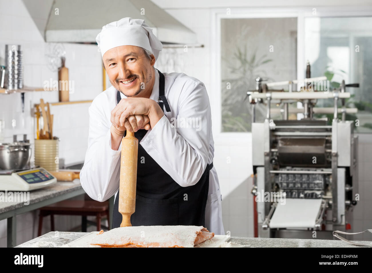 Happy Chef Holding Rolling Pin At Counter In Kitchen Stock Photo - Alamy