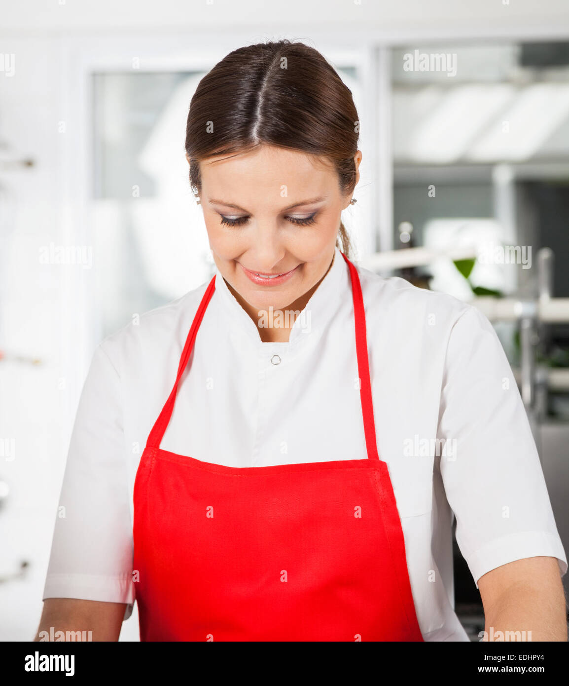 Smiling Female Chef In Red Apron At Kitchen Stock Photo - Alamy
