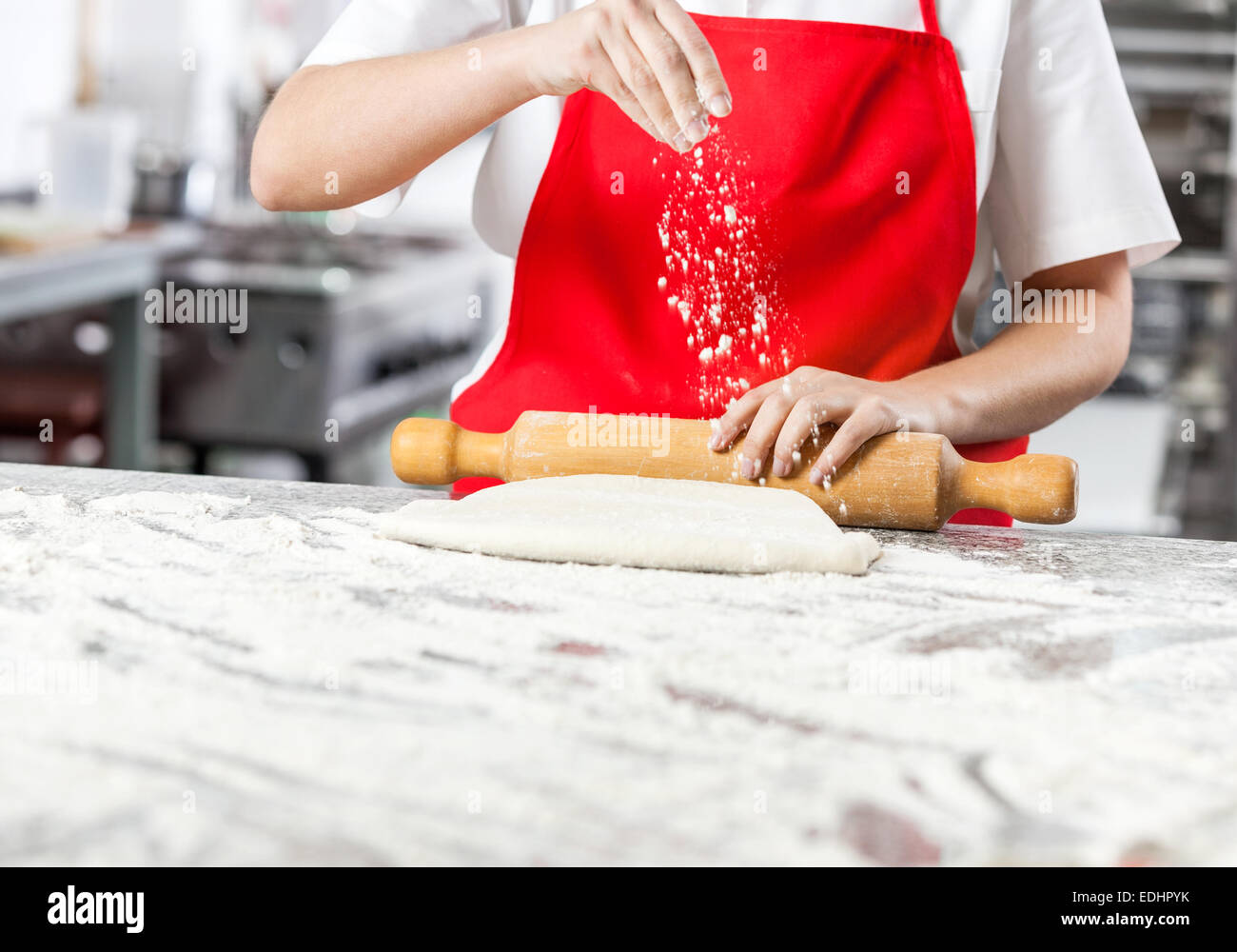 Chef Sprinkling Flour While Rolling Dough At Messy Counter Stock Photo ...