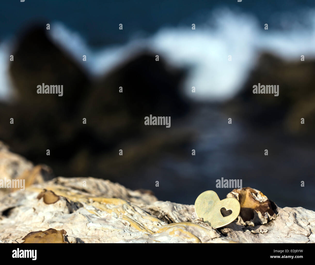 A bright beautiful metal heart is placed on top of a rock. In the ...