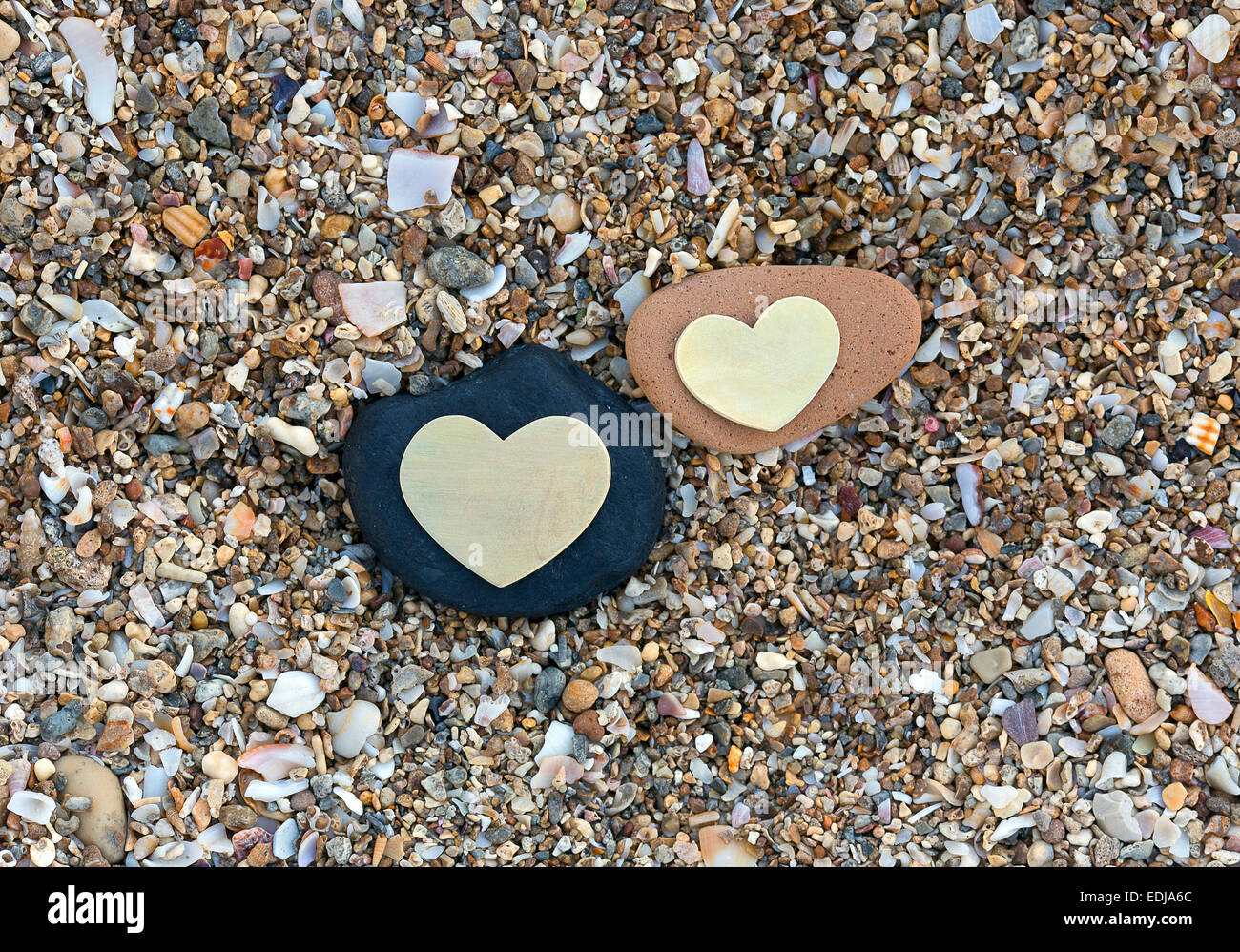 Two bright beautiful metal hearts are placed on two different rocks on ...