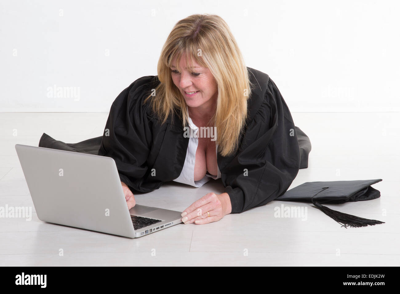 Mature university student using laptop computer wearing black gown ...