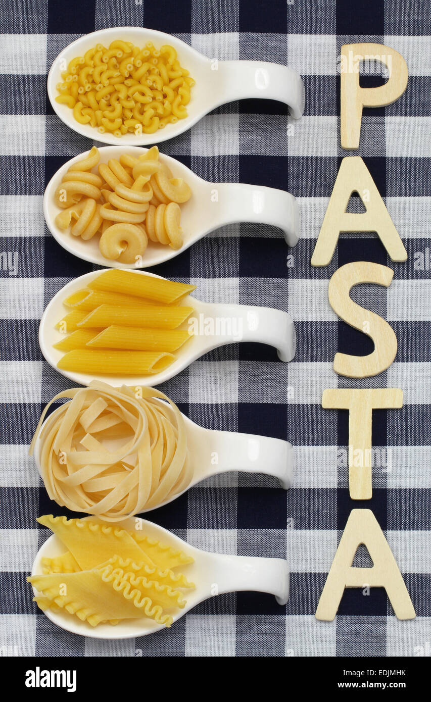 Pasta written with wooden letters on checkered cloth and uncooked pasta ...