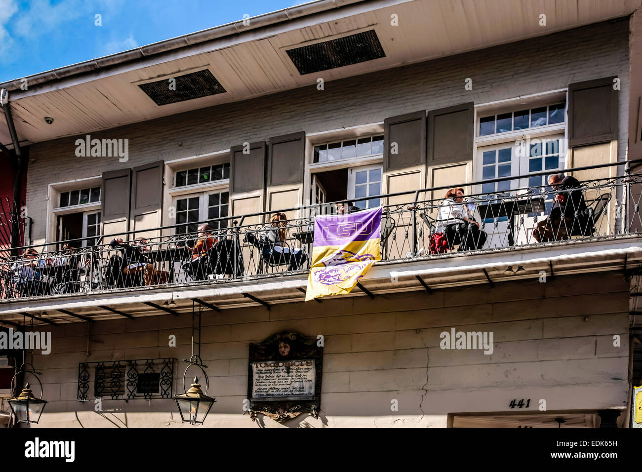 People sitting on a balcony looking down at the people below on Bourbon ...