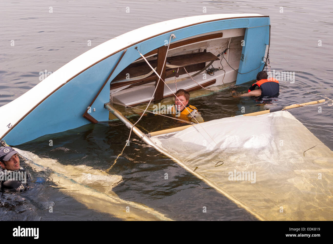 Three men practise capsizing their sailing boat in the Uk Stock Photo ...