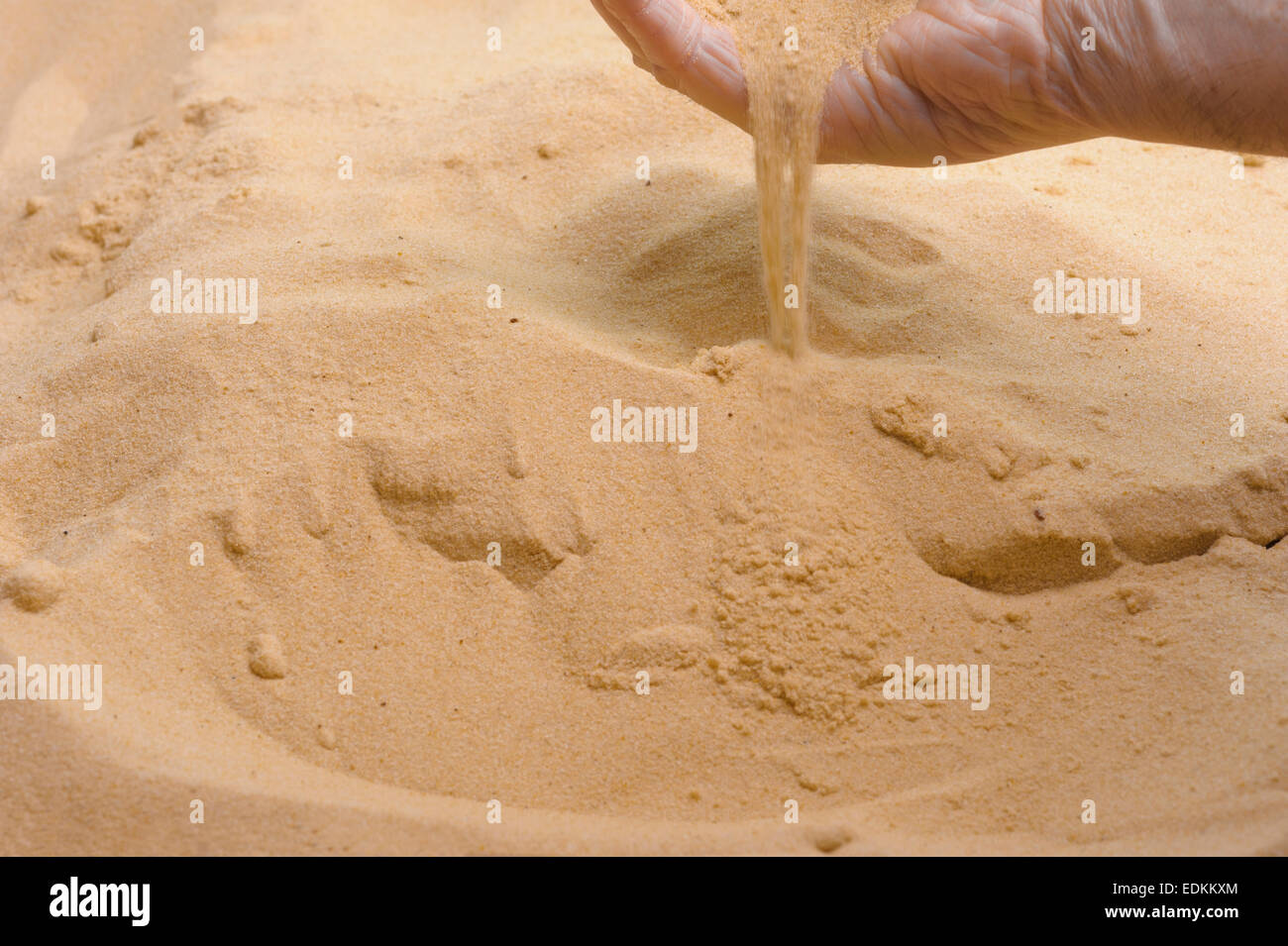 Mans hand with soft sand running through fingers Stock Photo - Alamy