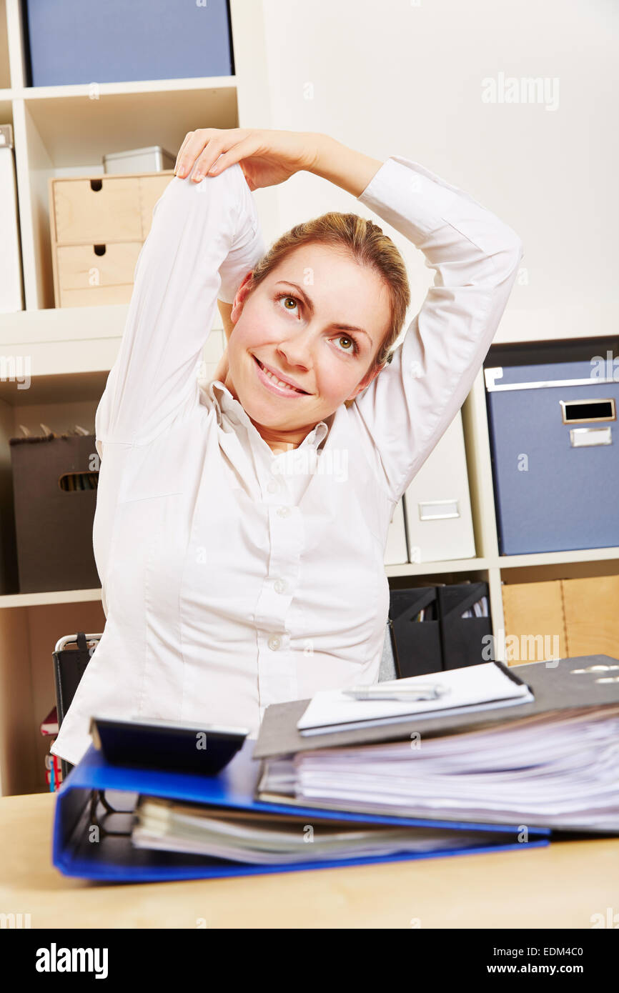 Smiling young business woman doing back training at her desk in the ...