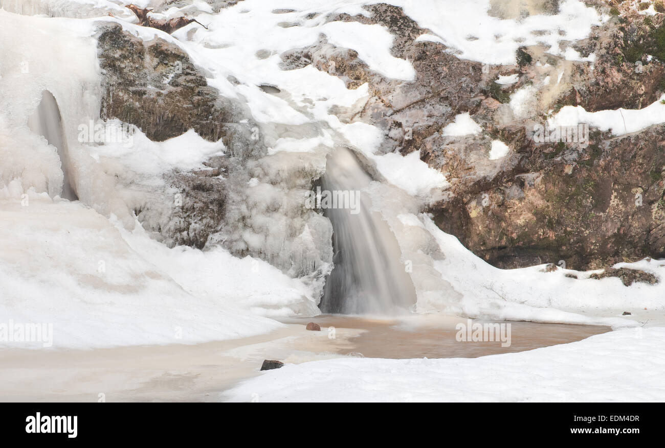 Frozen over waterfall with rocks and snow Stock Photo - Alamy