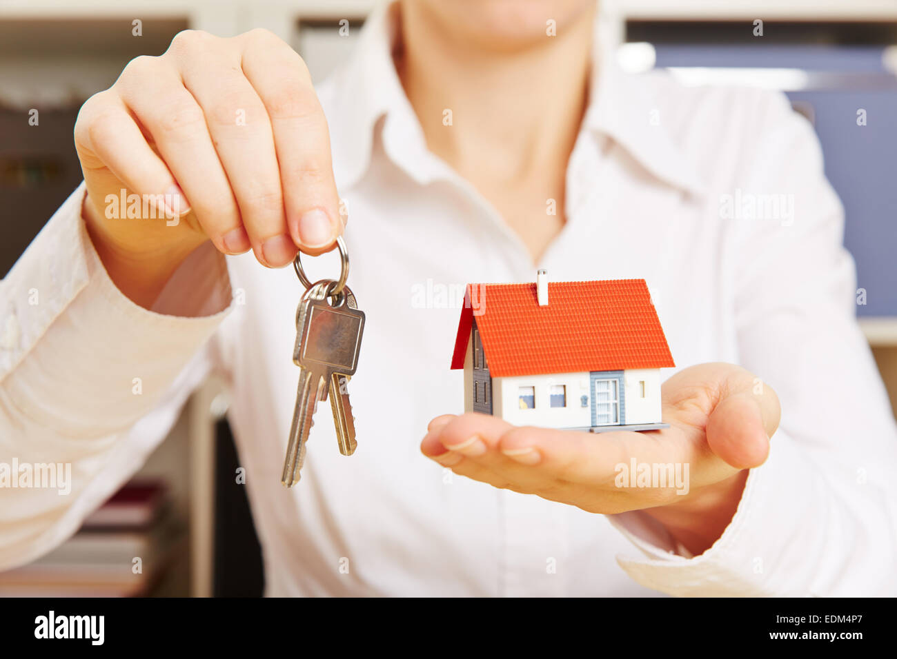 Hands of a woman holding two keys and a small house Stock Photo - Alamy