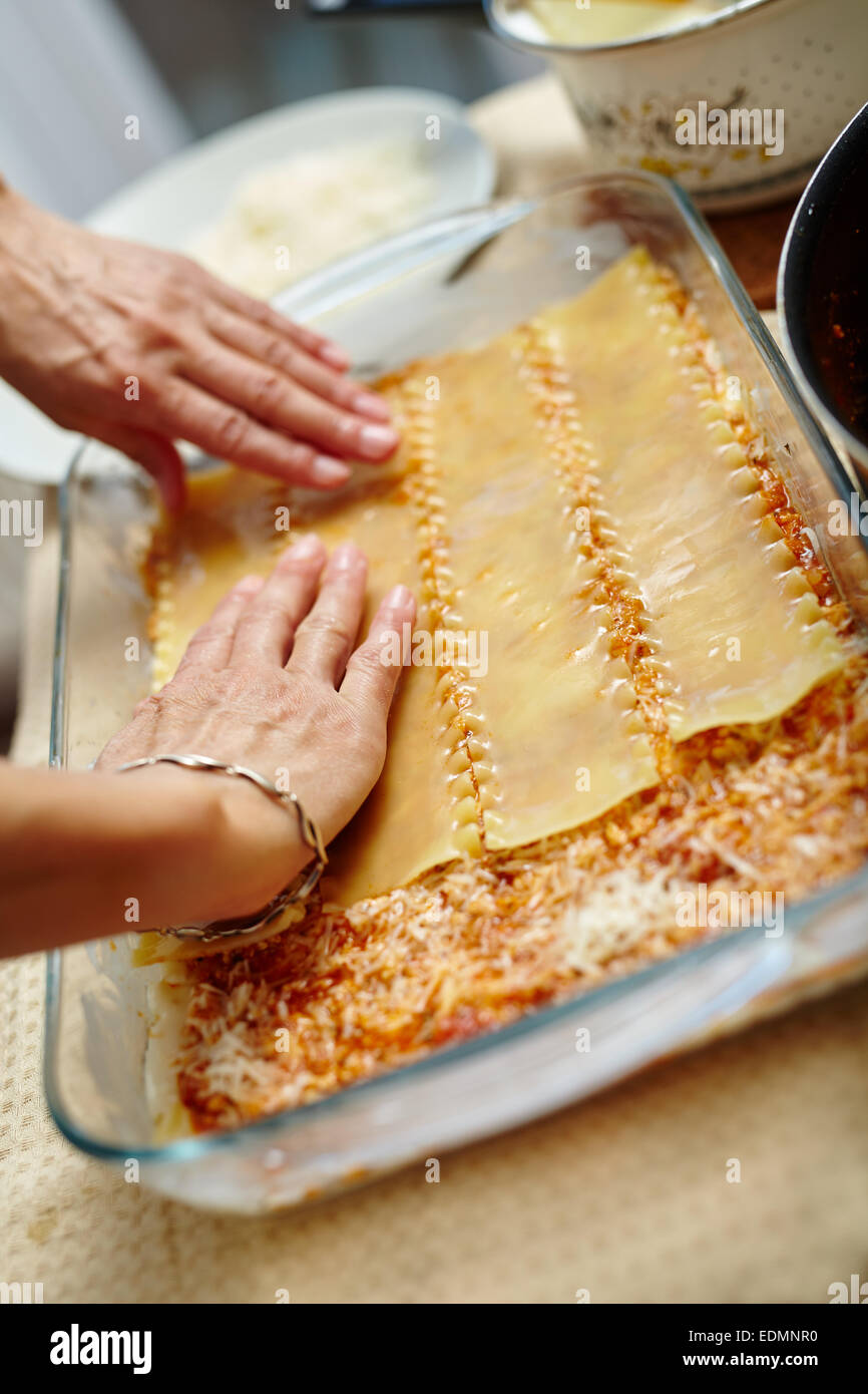 Woman cooking lasagna, arranging the pasta in a tray with filling Stock ...