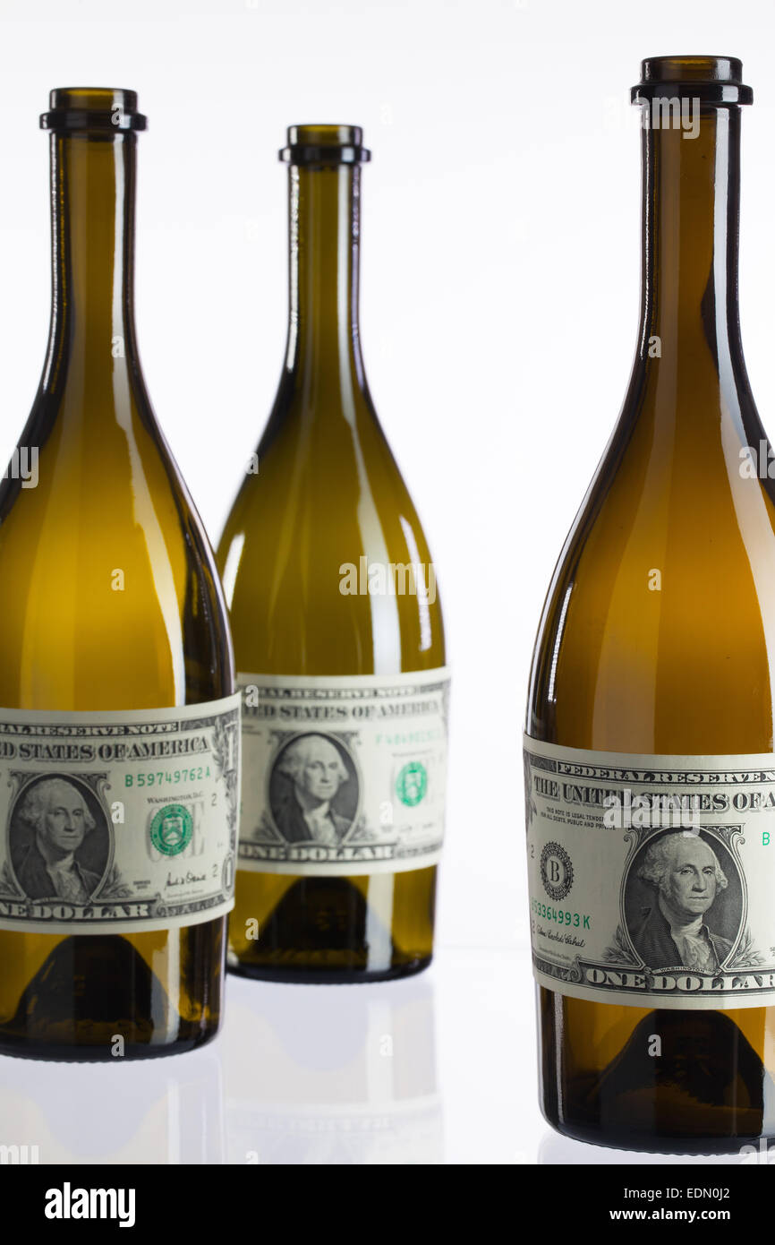 Empty bottles of wine from the label of dollar bill on a glass table ...