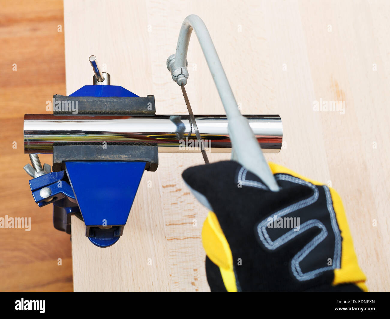 sanitary technician sawing chrome plated plumbing drain pipe gripped in ...