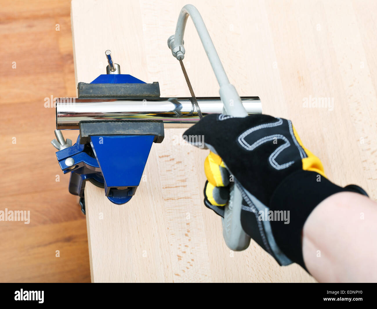 plumber saws metal trap pipe gripped in vice on wooden table by hacksaw ...