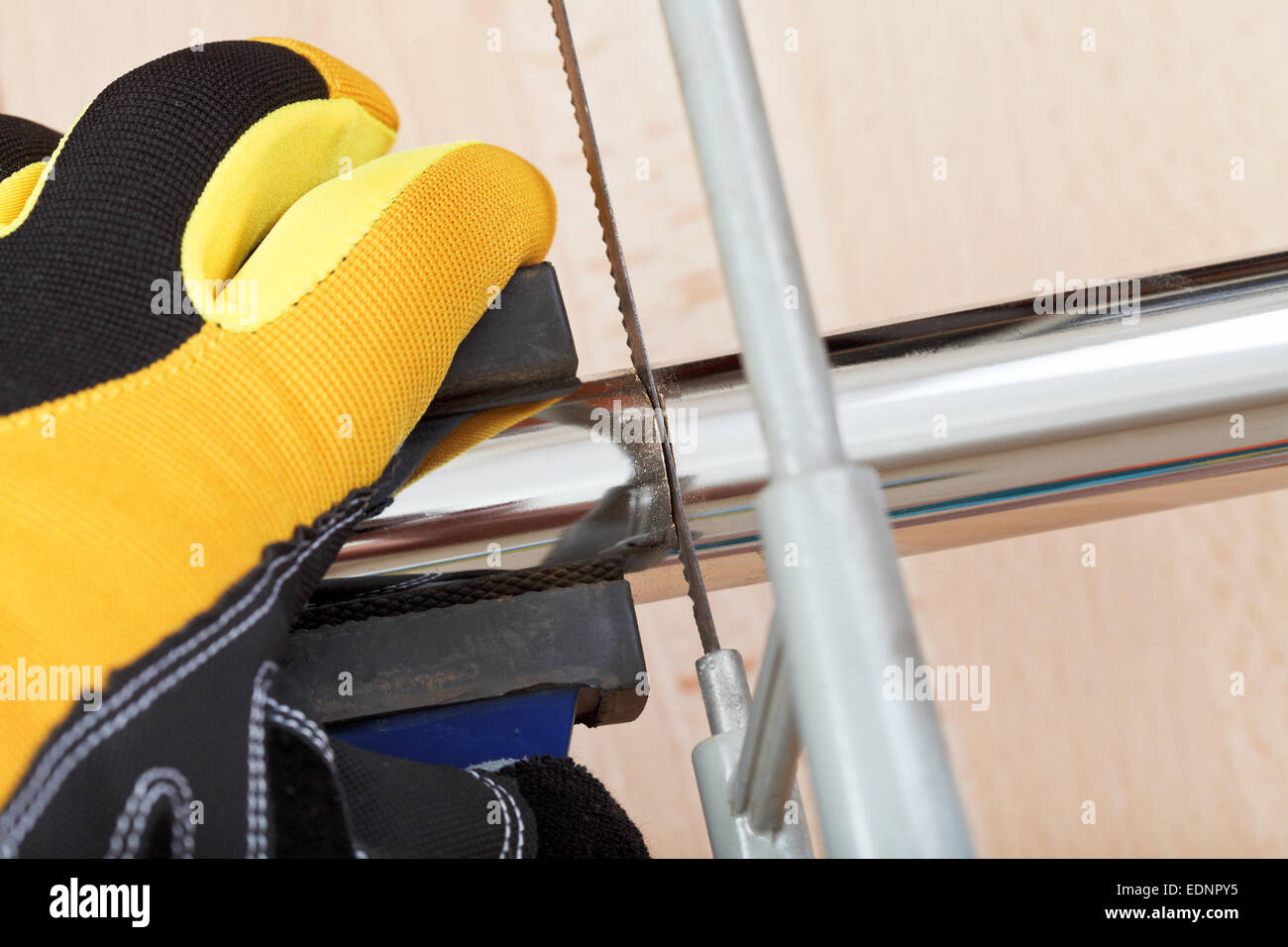 plumber sawing chromeplated drain pipe gripped in vice by hacksaw close ...