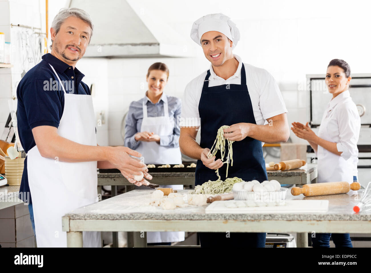 Happy Male And Female Chefs Preparing Pasta At Kitchen Stock Photo - Alamy