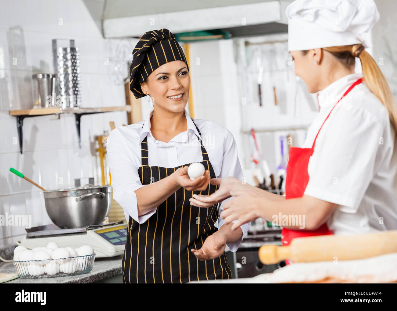 Smiling Chef Giving Eggs To Colleague In Kitchen Stock Photo - Alamy