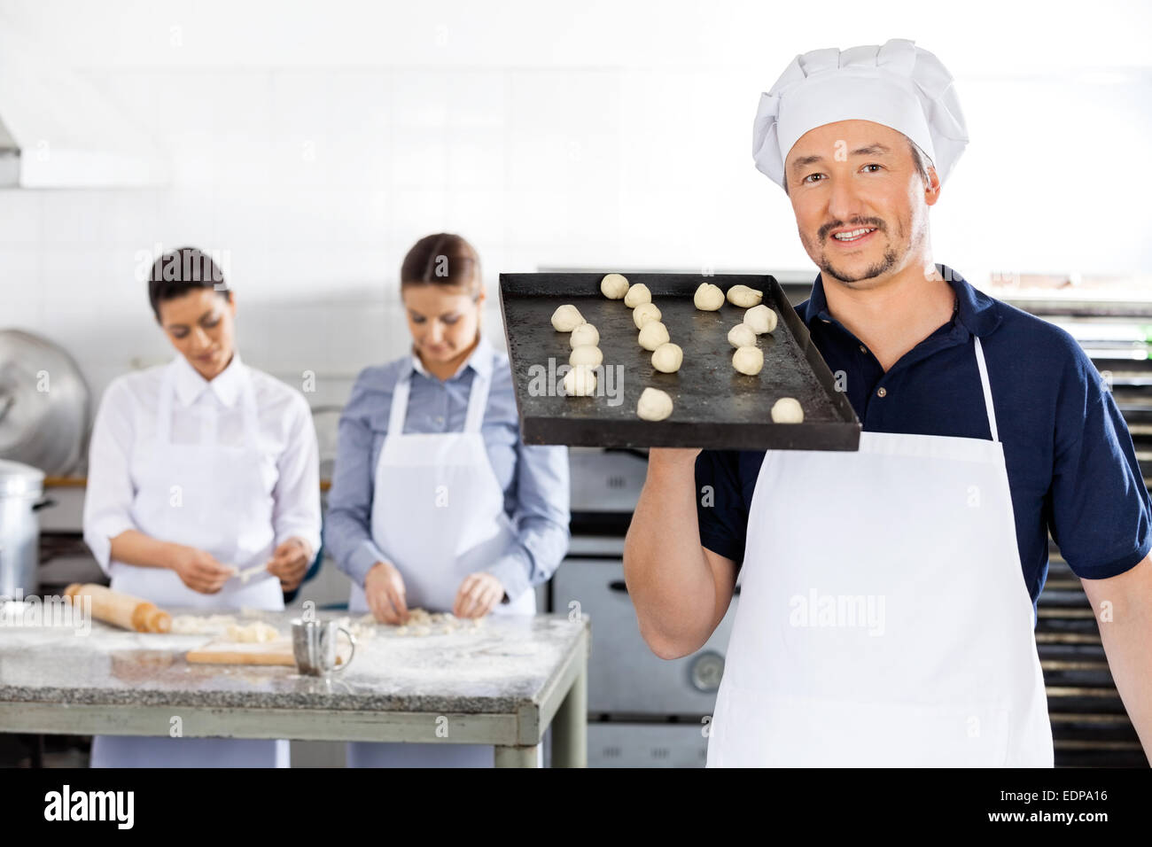 Smiling Chef Carrying Baking Sheet With Dough Balls At Kitchen Stock ...