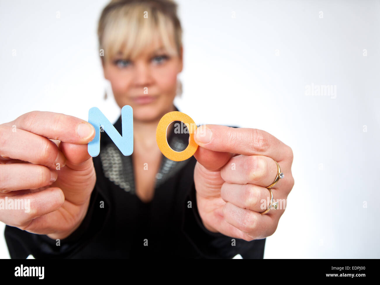 Studio portrait of a cute blond girl holding two letters forming NO ...