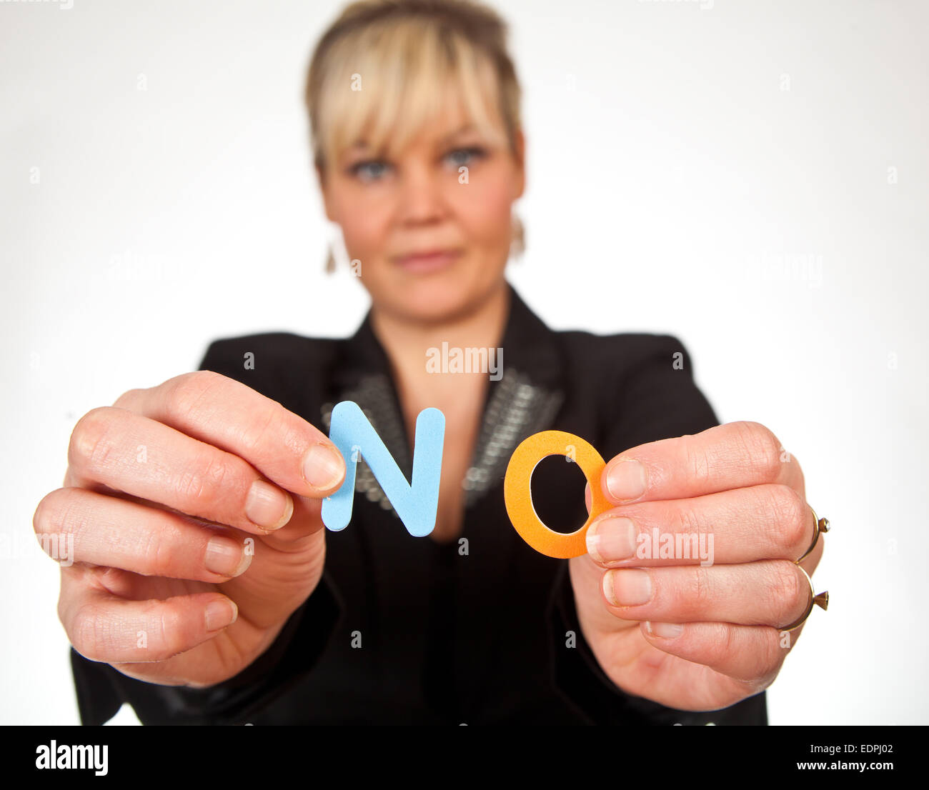 Studio portrait of a cute blond girl holding two letters forming NO ...